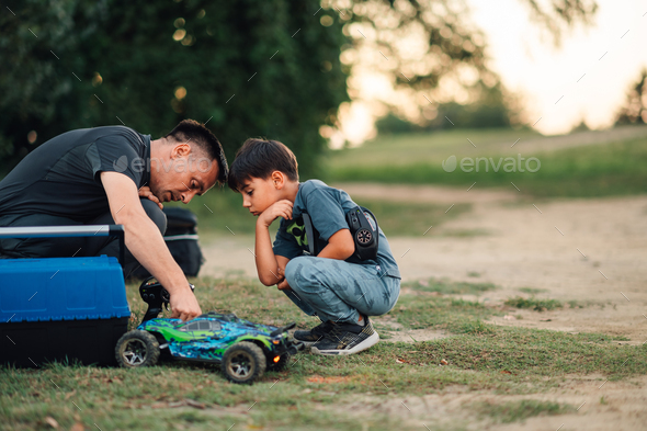 Father and his son examining a damaged toy car while playing outside Stock Photo by zamrznutitonovi